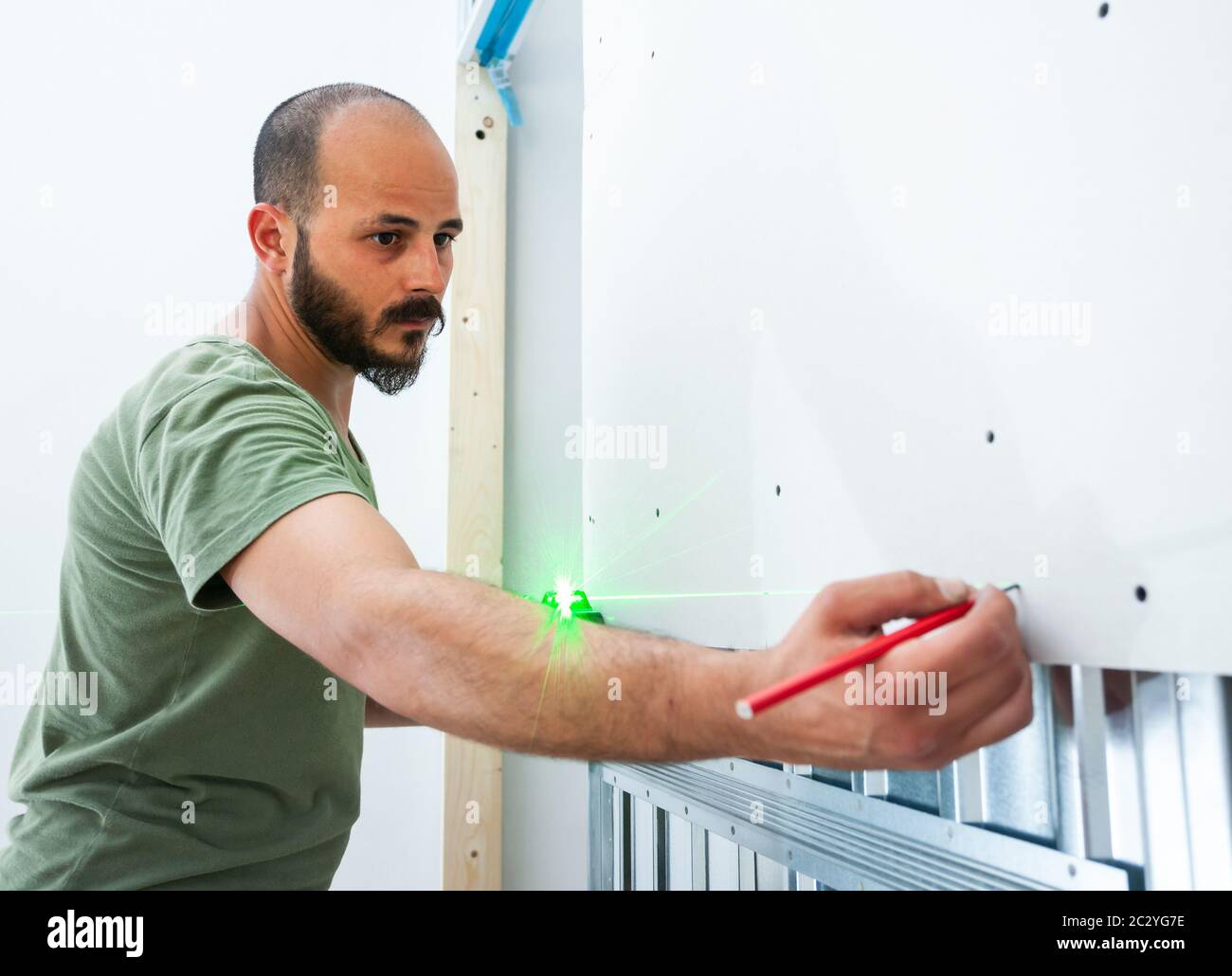 Worker building plasterboard wall. Working with cutting tools, fixing ...