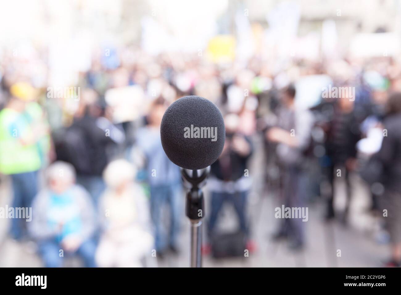 Microphone in focus, blurred crowd in the background. Political rally ...