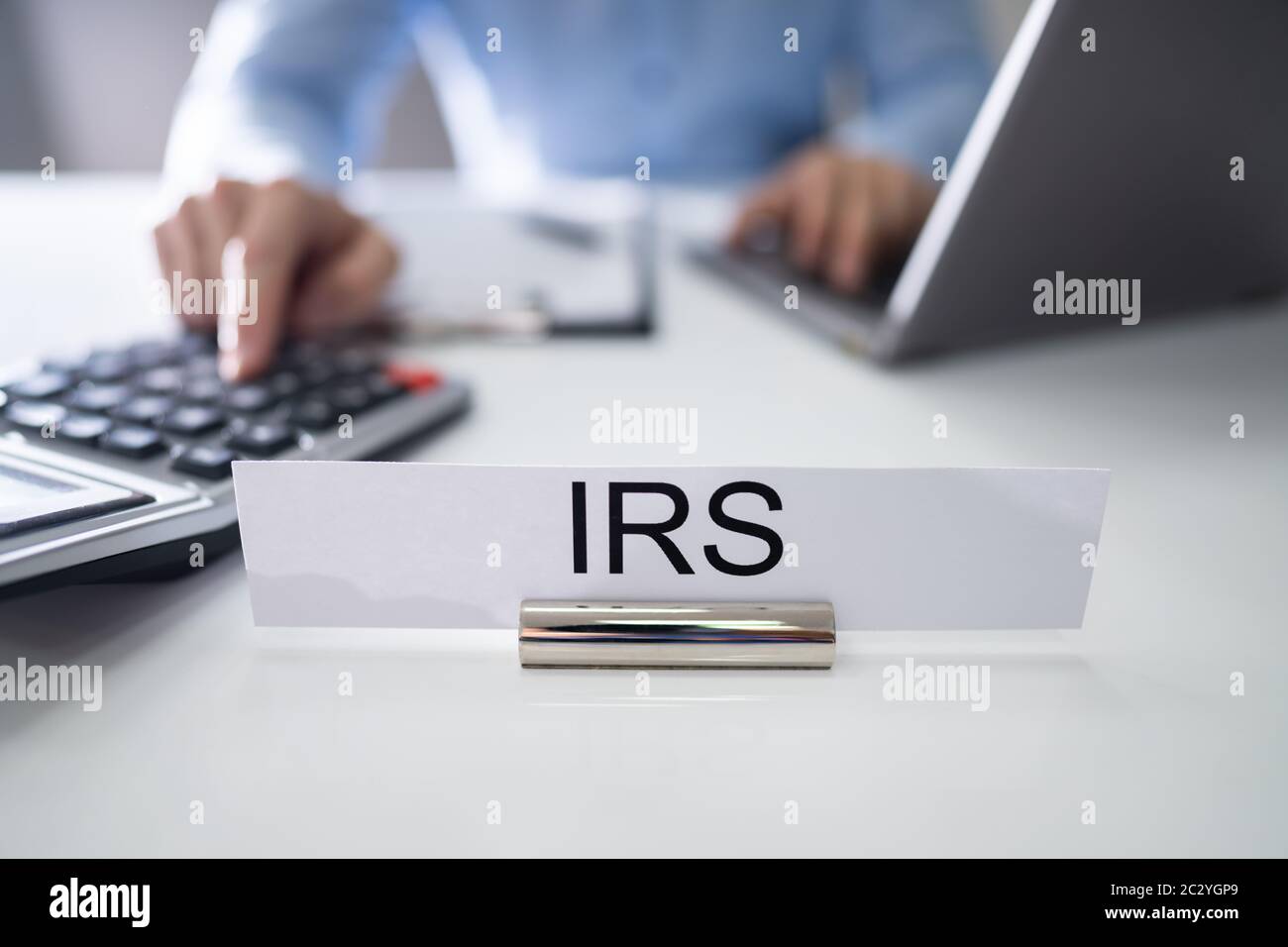 IRS Nameplate In Front Of Accountant Calculating Tax On Desk With ...