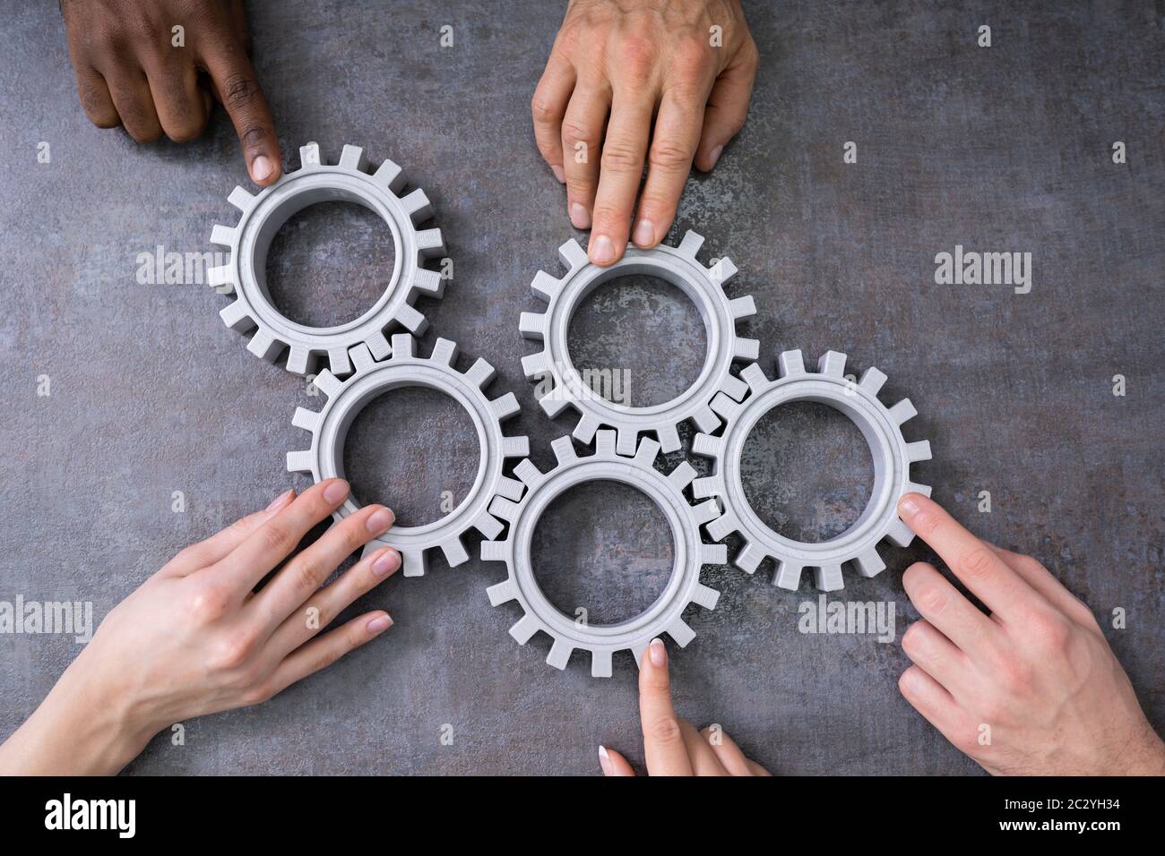 Group Of Businesspeople Joining Together Gears On Table At Workplace ...