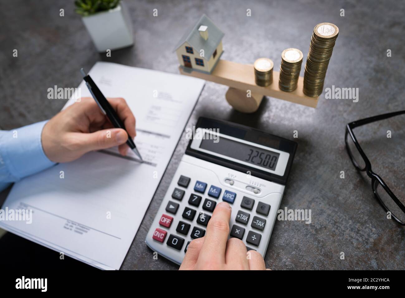 Man Calculating Bill Near House Model And Stacked Coins Balancing On ...