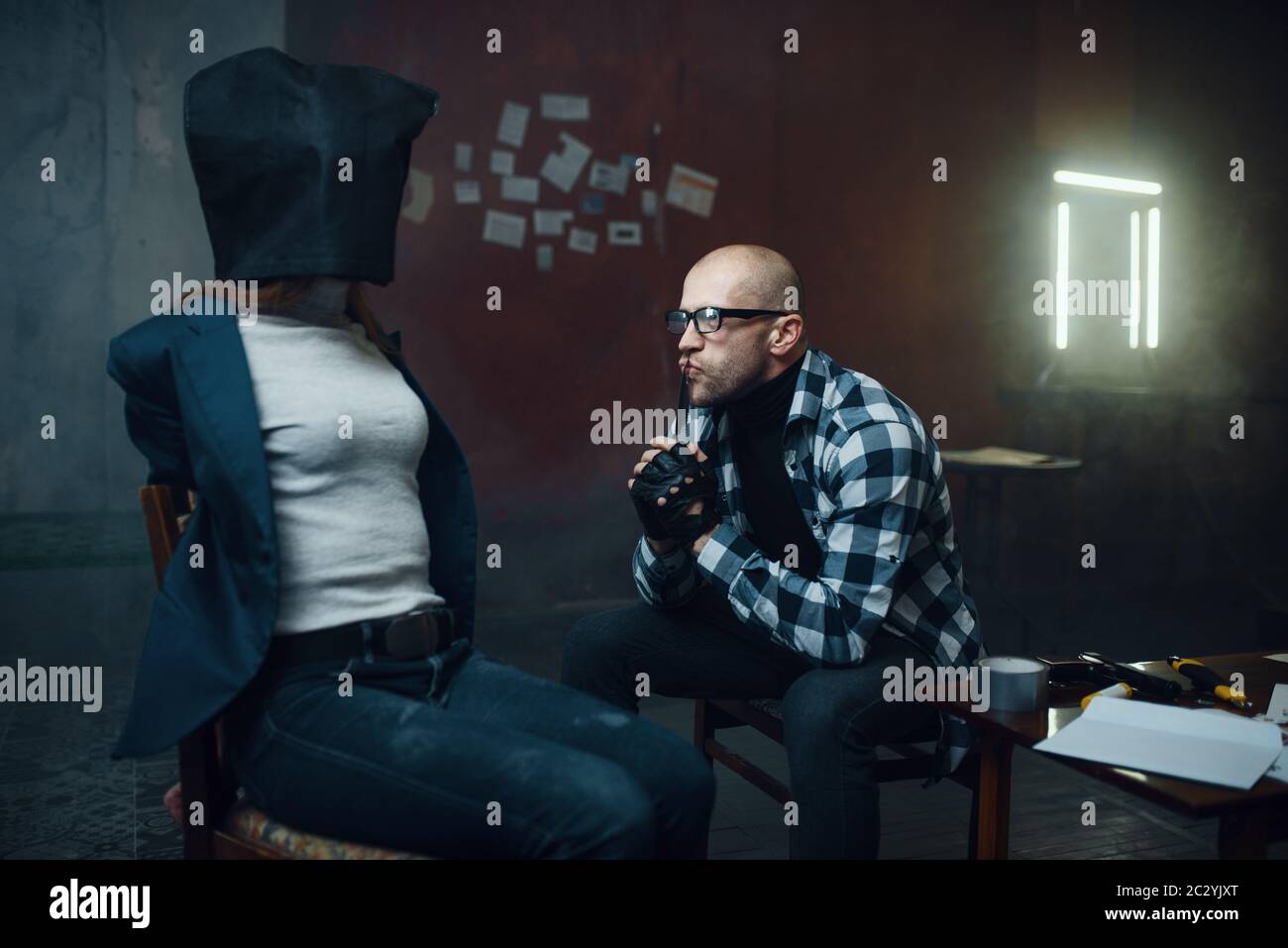 Maniac kidnapper looks on his female victim with a bag on her head ...