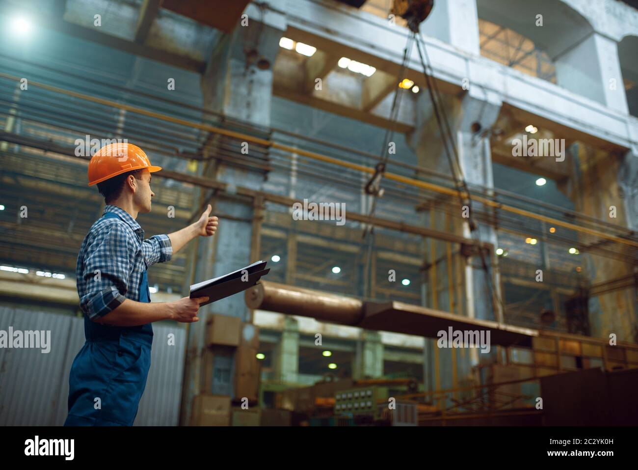Master shows thumbs up to crane operator on metal factory. Metalworking ...