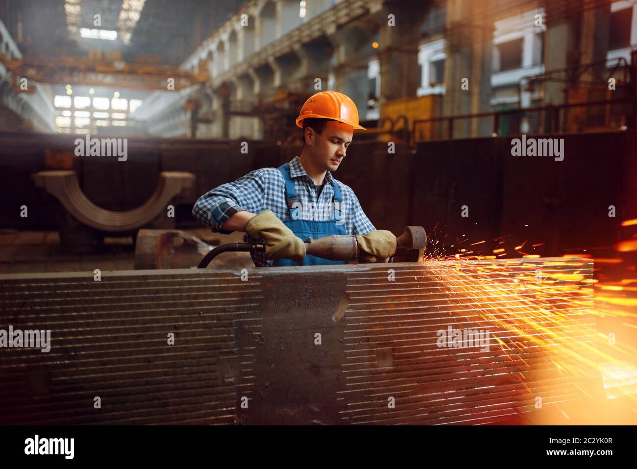 Male worker in uniform and helmet works with metal workpieces on ...