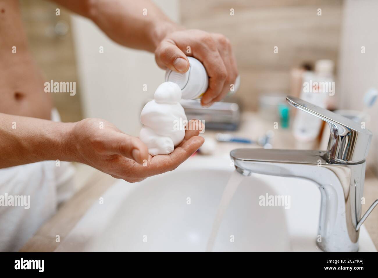 Man squeezes out shaving foam on hand in bathroom, routine morning ...