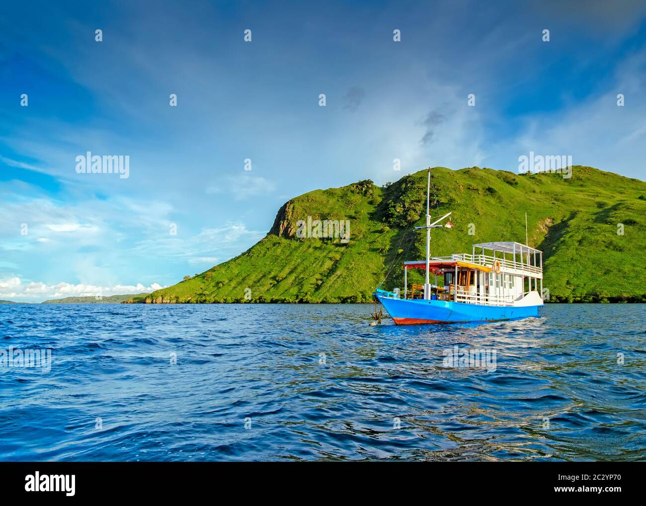 Little lonely boat on the background of a green hill. Lesser Sunda ...