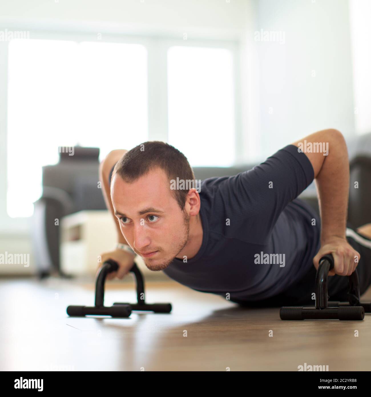Handsome young man working out at home, using his own bodyweight for ...