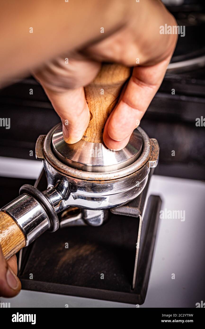 Barista presses ground coffee using tamper Stock Photo - Alamy