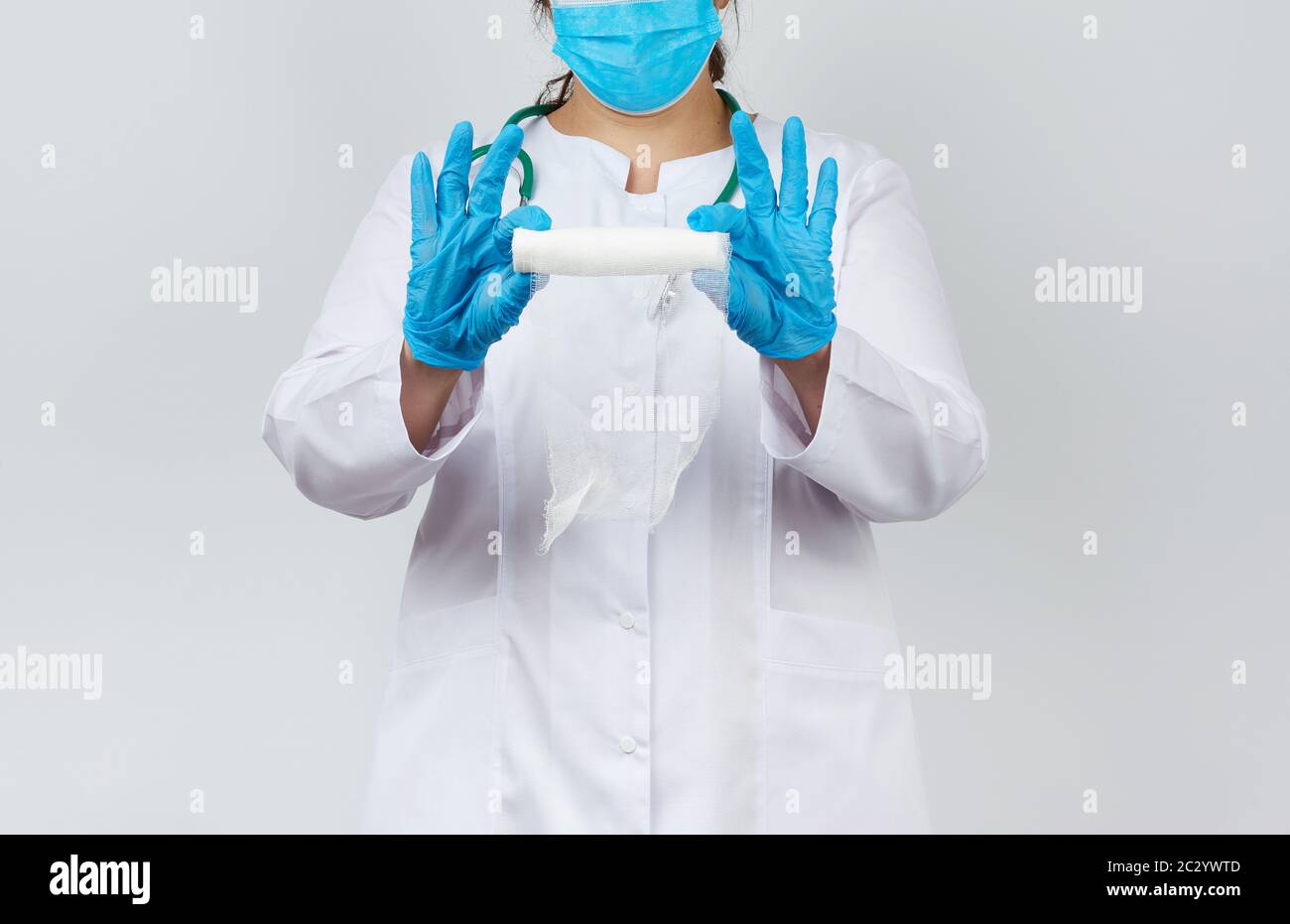 medic woman in white coat and mask holds a twisted gauze bandage for ...