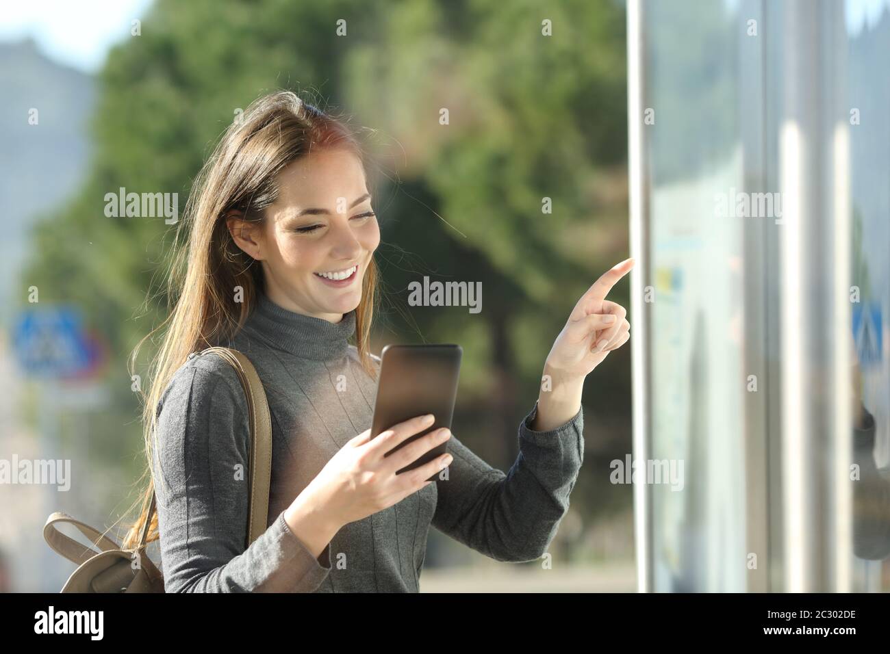 Happy commuter checks smart phone and schedule table waiting for ...