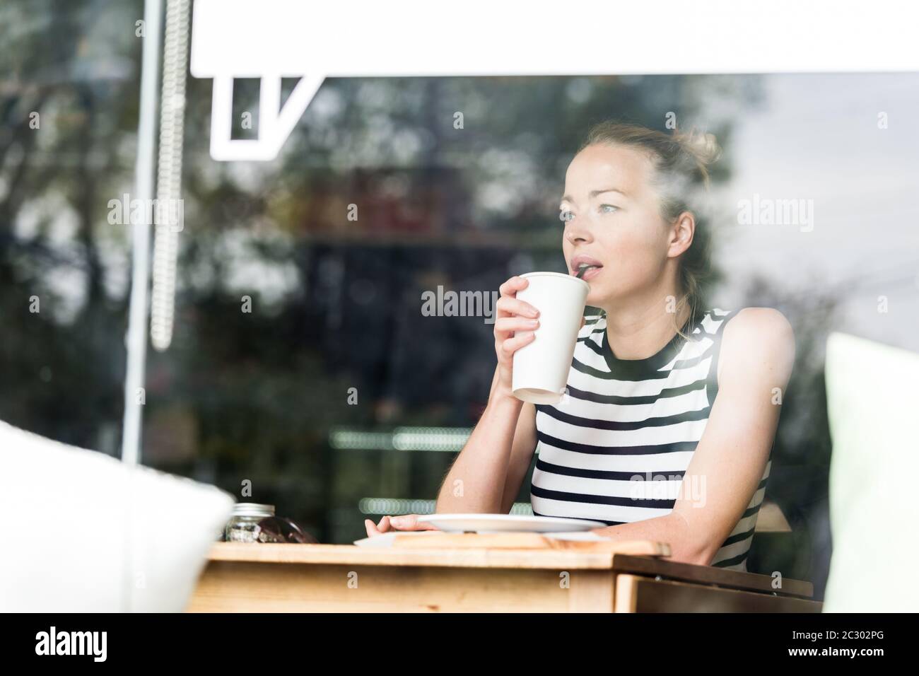 Young caucasian woman sitting alone in coffee shop drinking american ...