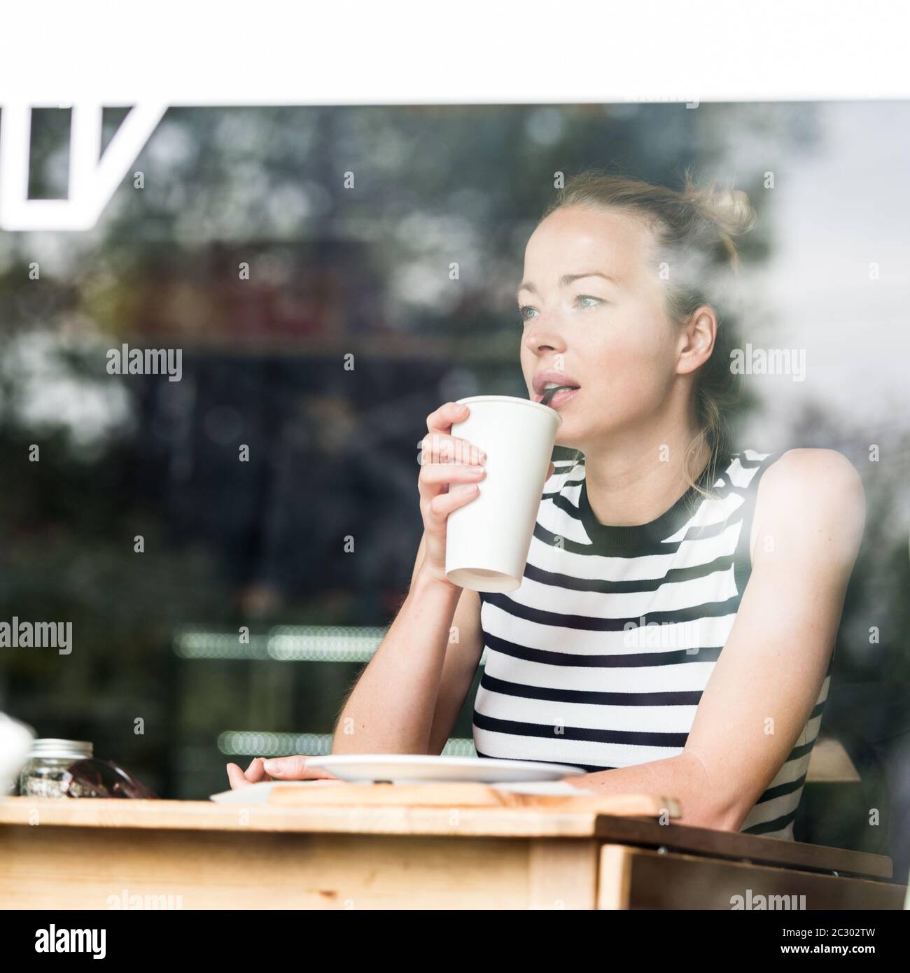 Young caucasian woman sitting alone in coffee shop drinking american ...