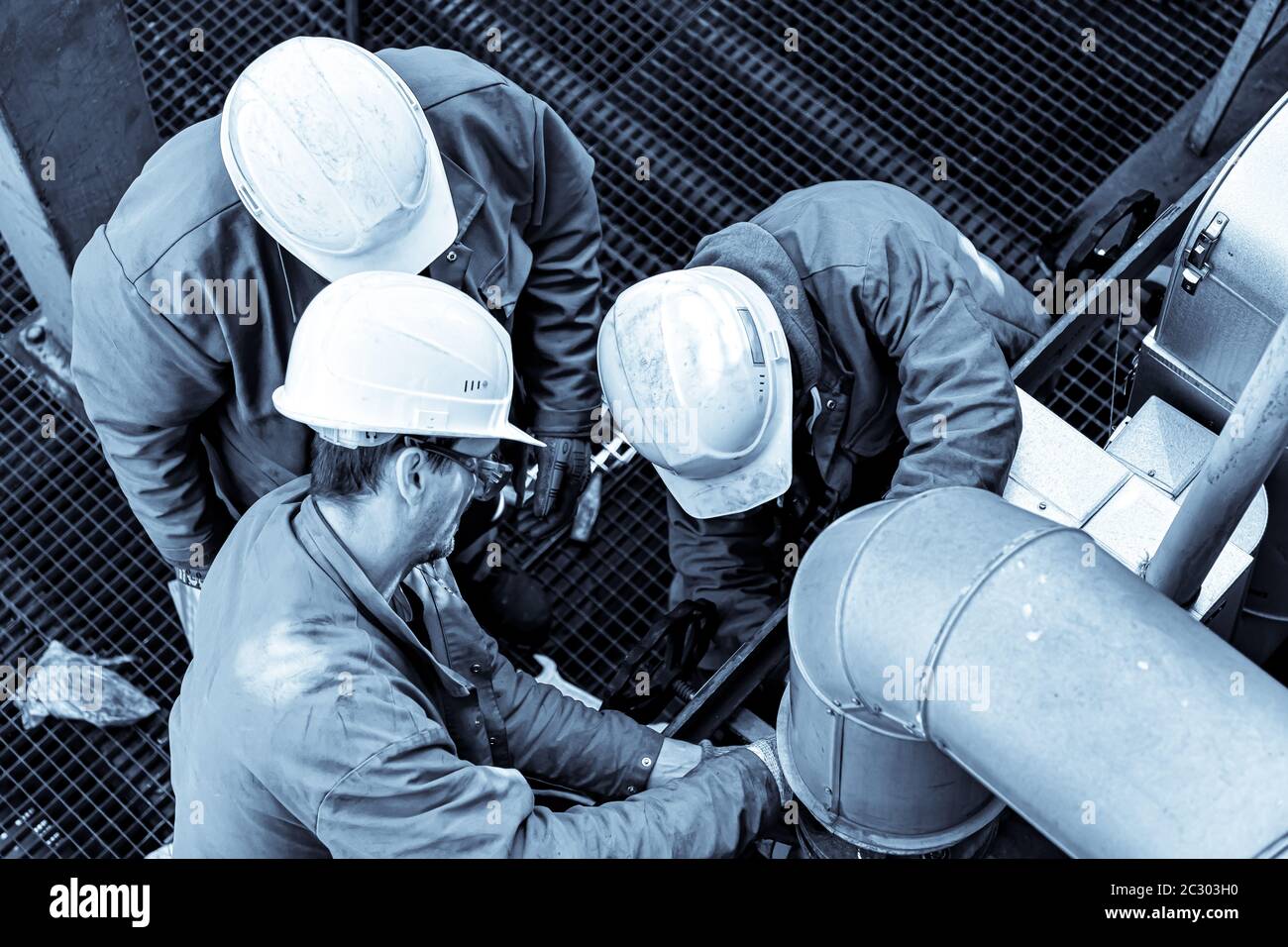 A group of mechanic wearing blue clothes, white helmets and personal ...