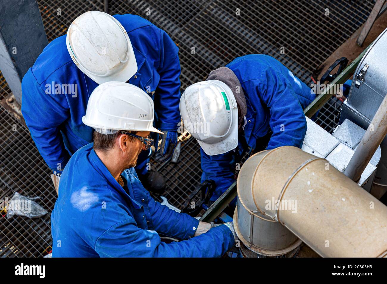 A group of mechanic wearing blue clothes, white helmets and personal ...