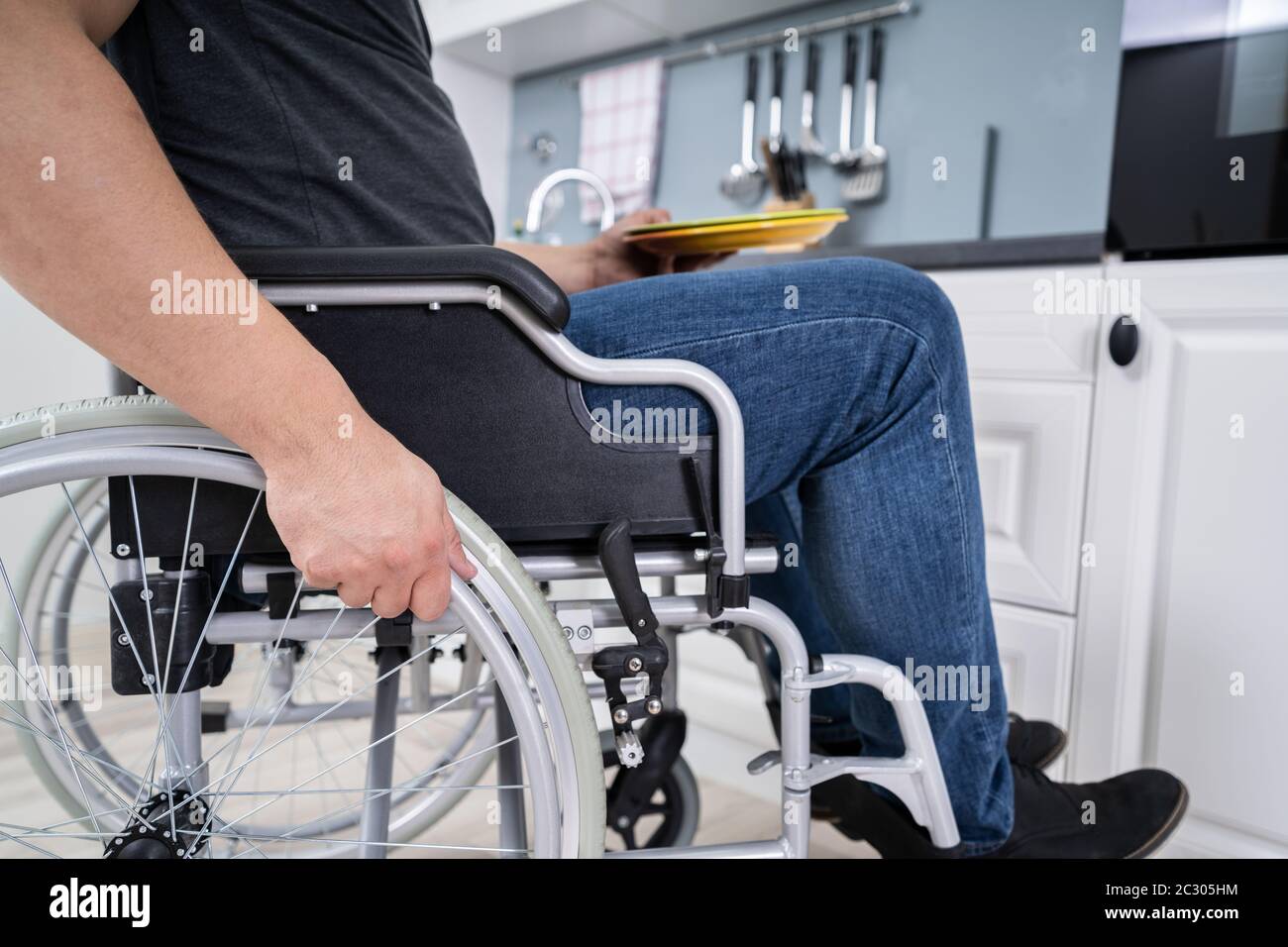 Handicapped Man Sitting On Wheelchair In Kitchen Holding Dishes Stock ...