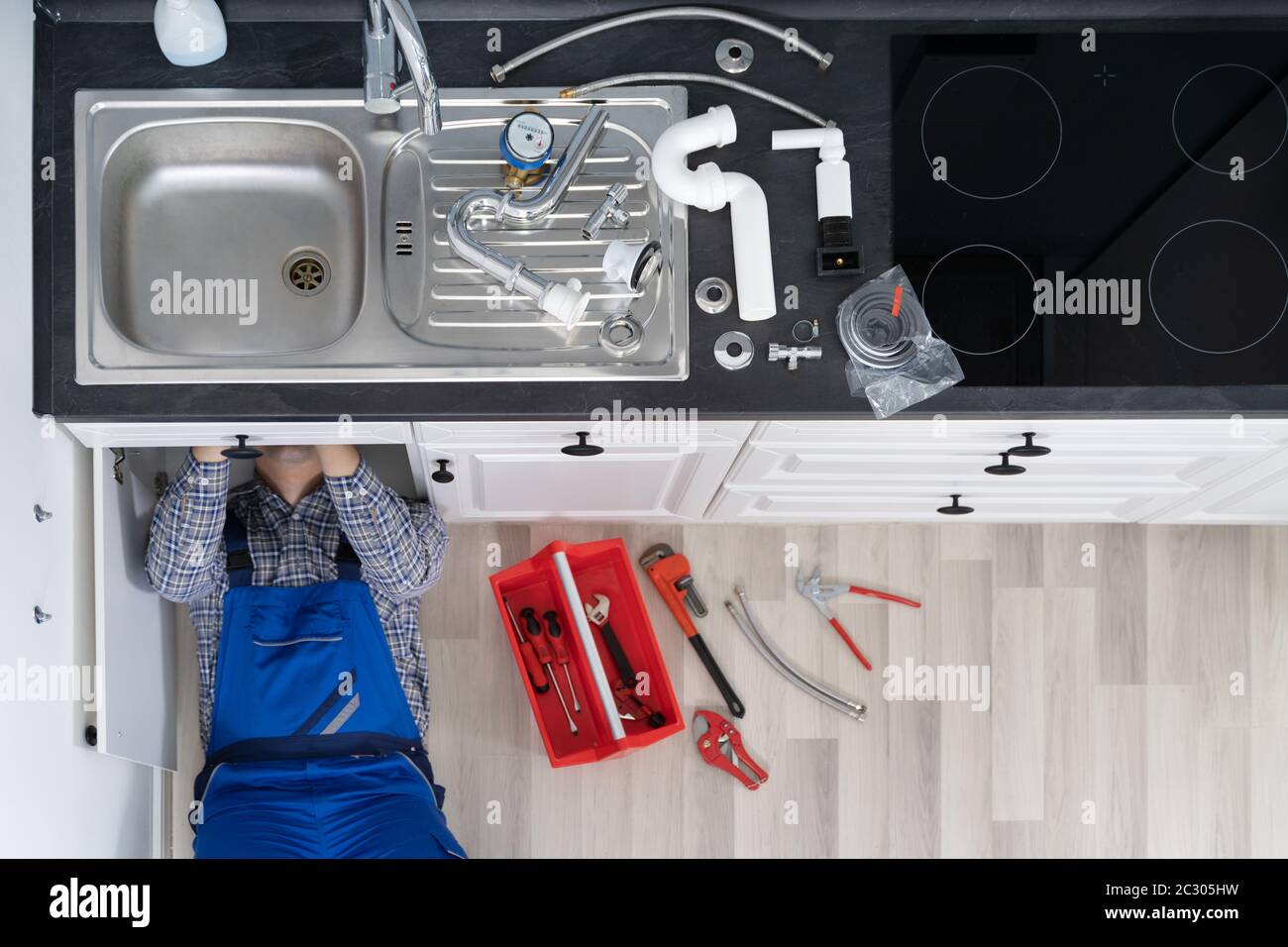 Worker Lying On Floor Repairing Kitchen Sink With Adjustable Wrench ...