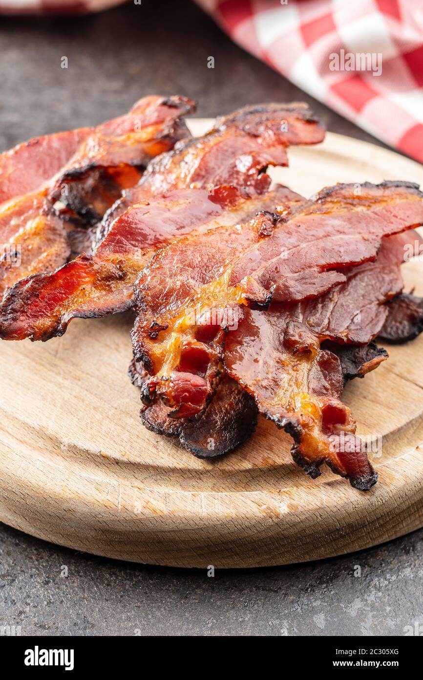 Fried bacon on cutting board. Sliced roasted bacon on old kitchen table ...