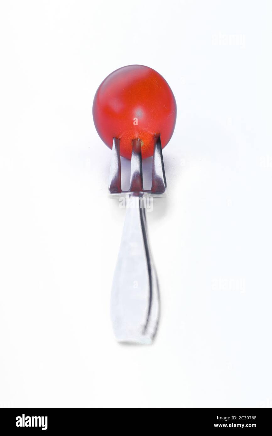 Round cherry tomato pricking with a fork with white background Stock ...