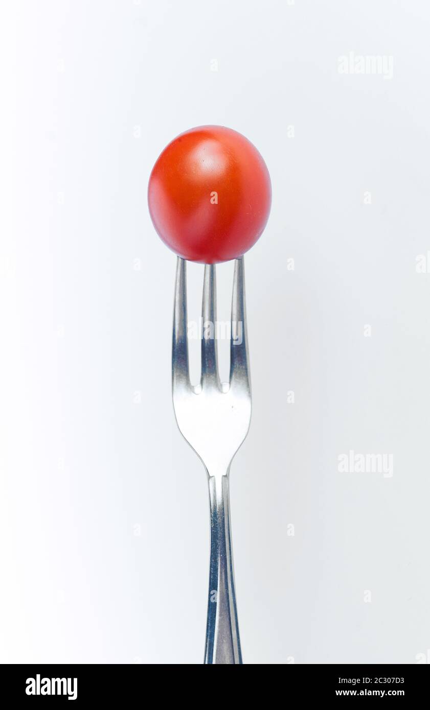 Round cherry tomato pricking with a fork with white background Stock ...