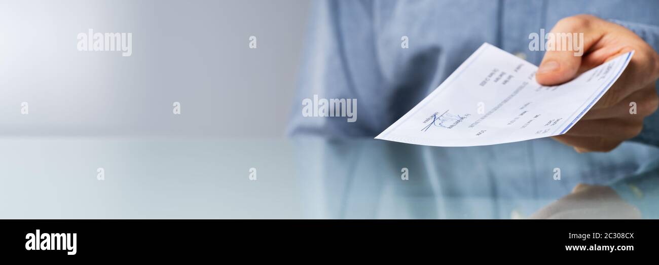 Close-up Of A Human Hand Giving Cheque On Desk Stock Photo - Alamy
