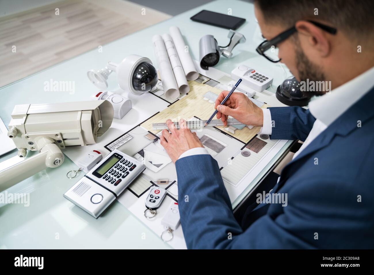 Architect Drawing Blueprint With Various Security Equipment On Desk ...