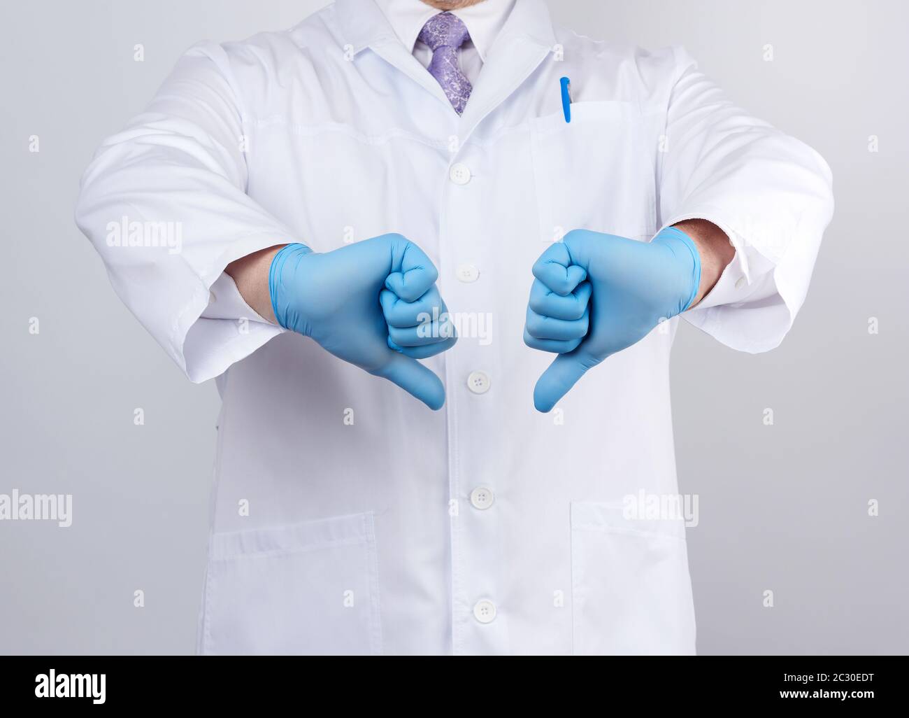 doctor in a white coat with buttons shows a gesture of dislike with his ...