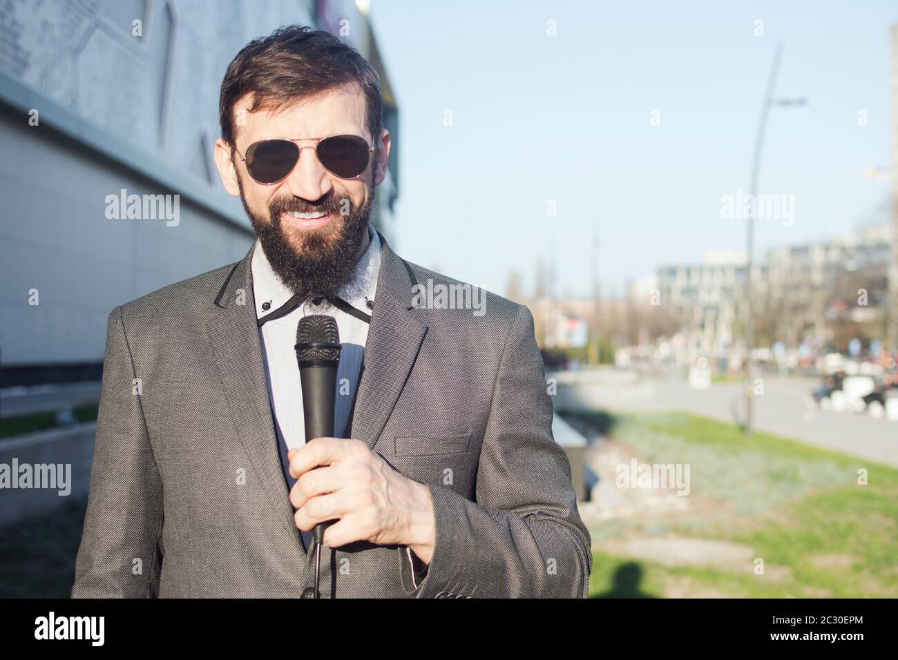 The journalist or anchorman or TV reporter is outdoors on the street in ...