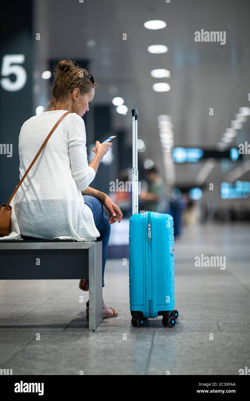 Young woman with her luggage at an international airport, waiting for ...