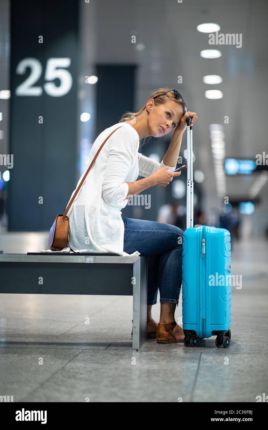 Young woman with her luggage at an international airport, waiting for ...