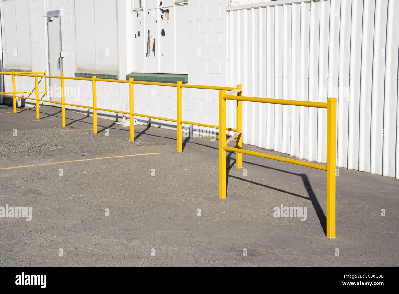 Yellow fences for walkway close to white wall of factory Stock Photo ...