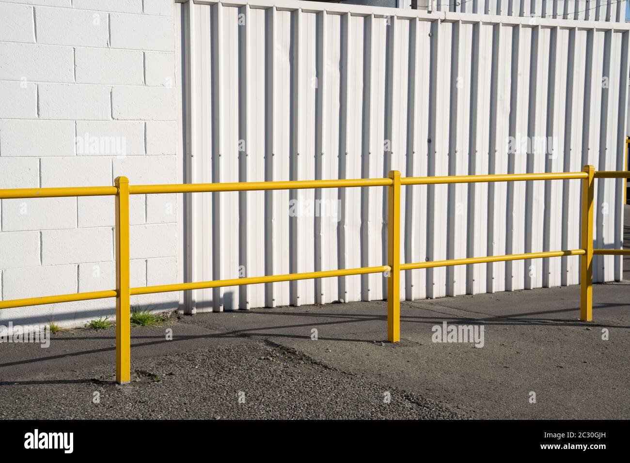 Yellow fences for walkway close to white wall of factory Stock Photo ...