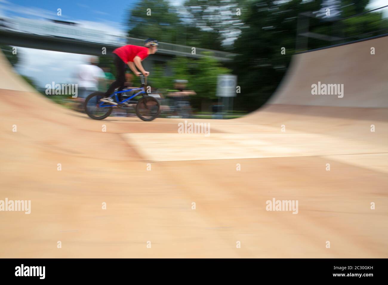 Bmx rider jumping over on a U ramp in a skatepark (motion blurred image ...