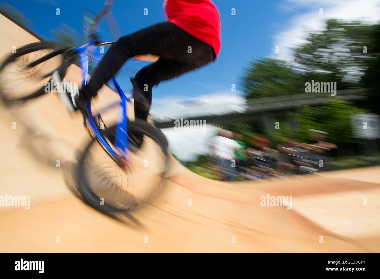 Bmx rider jumping over on a U ramp in a skatepark (motion blurred image ...