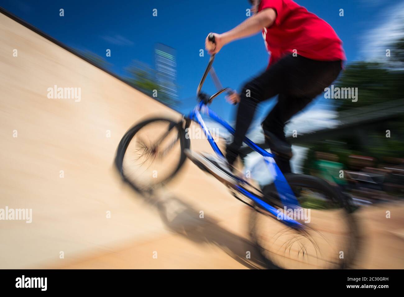 Bmx rider jumping over on a U ramp in a skatepark (motion blurred image ...