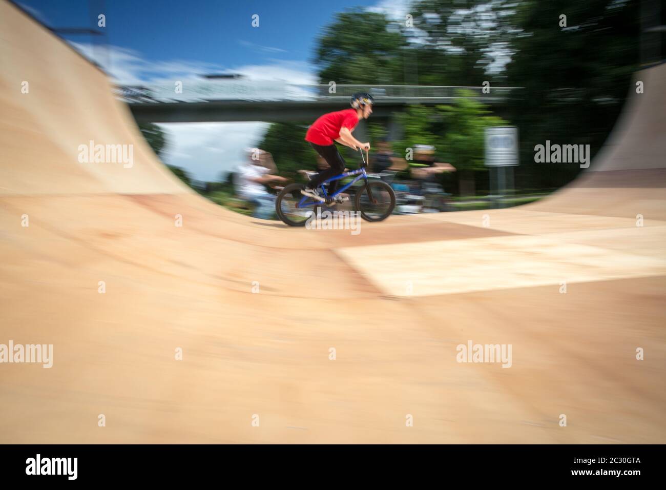 Bmx rider jumping over on a U ramp in a skatepark (motion blurred image ...