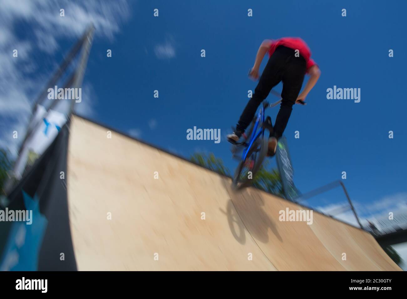 Bmx rider jumping over on a U ramp in a skatepark (motion blurred image ...