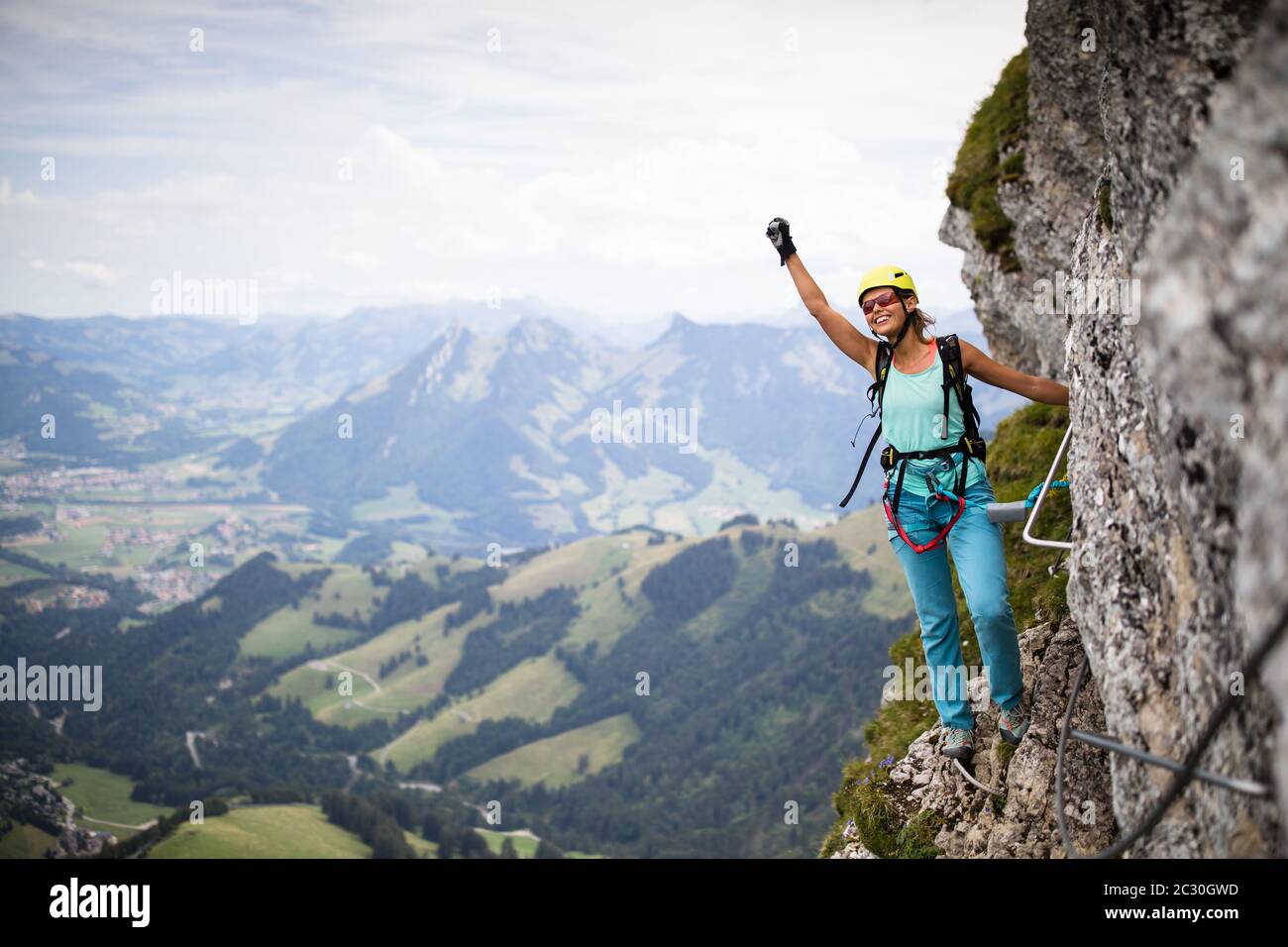 Pretty, female climber on a via ferrata - climbing on a rock in Swiss ...