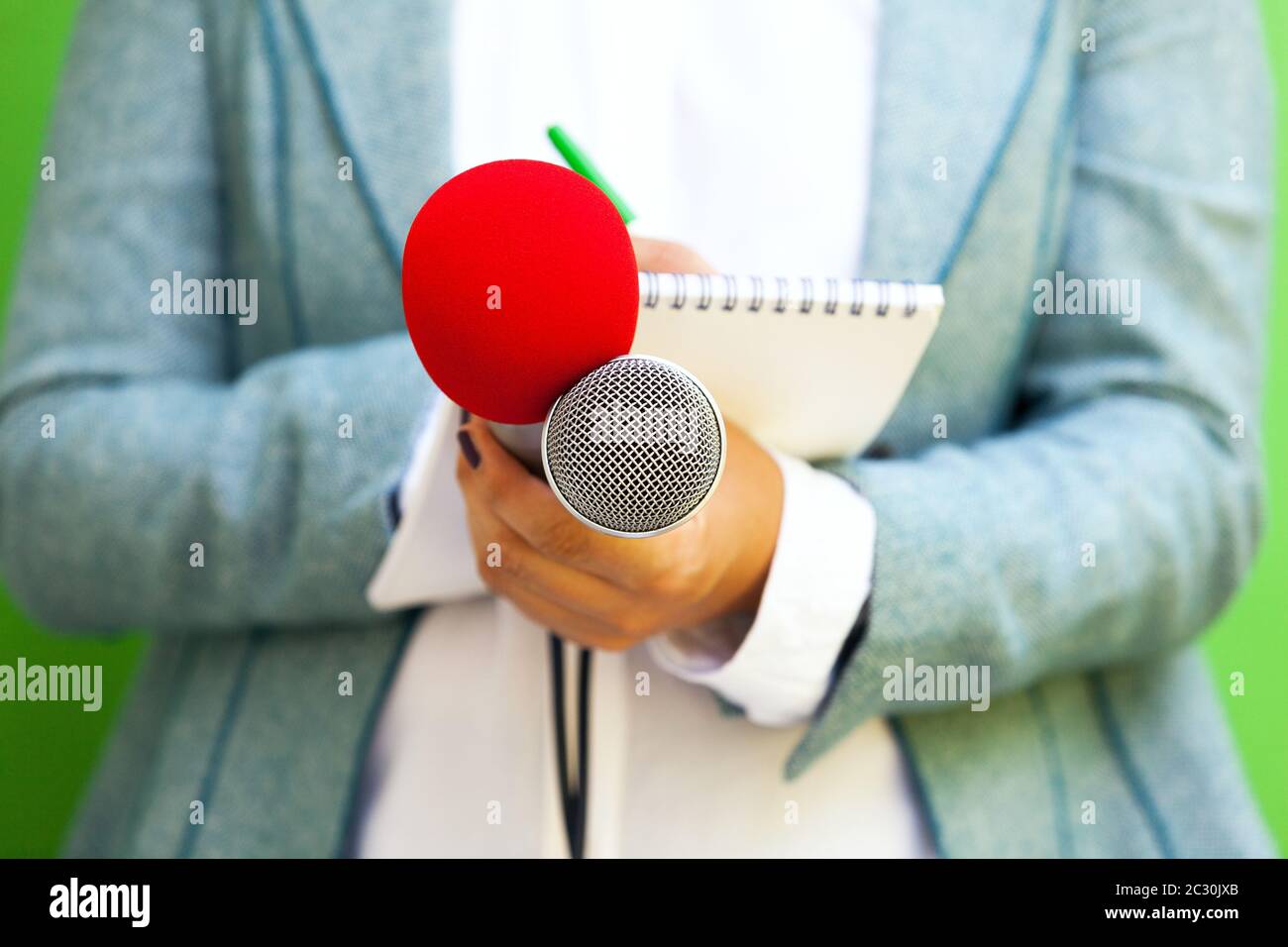 Female reporter at press conference, writing notes, holding microphone ...