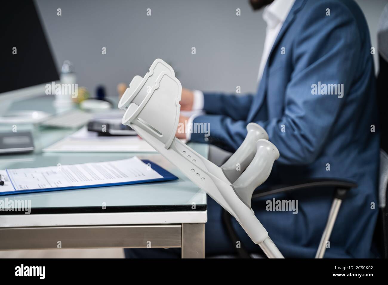 Close-up Of Crutches Leaning On Table In Front Of Handicapped Man ...