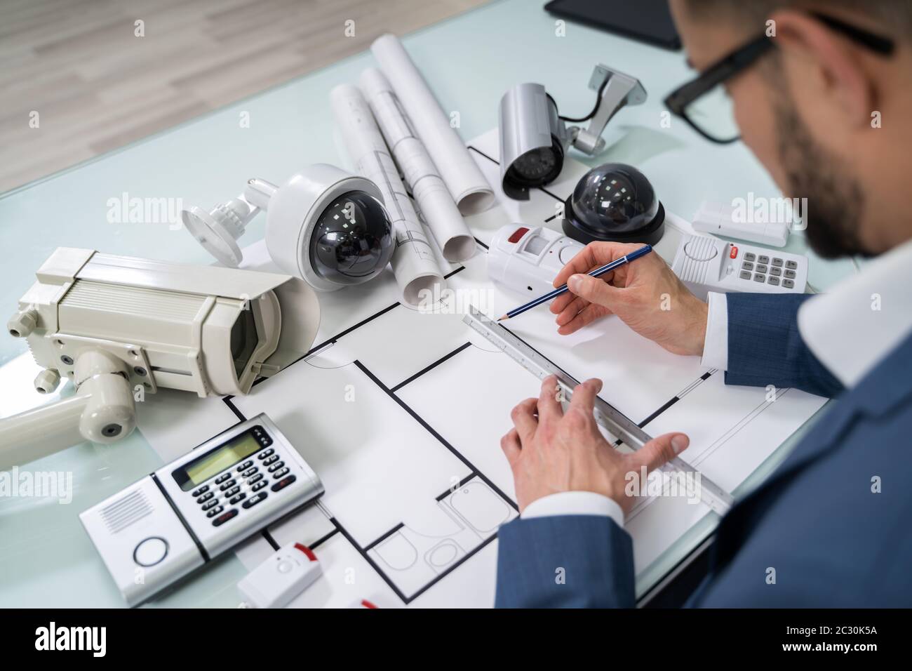 Architect Drawing Blueprint With Various Security Equipment On Desk ...