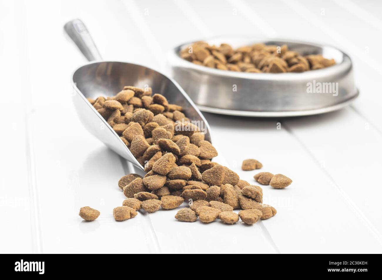 Dried kibble pet food in scoop. Heart shape dried animal food on white ...