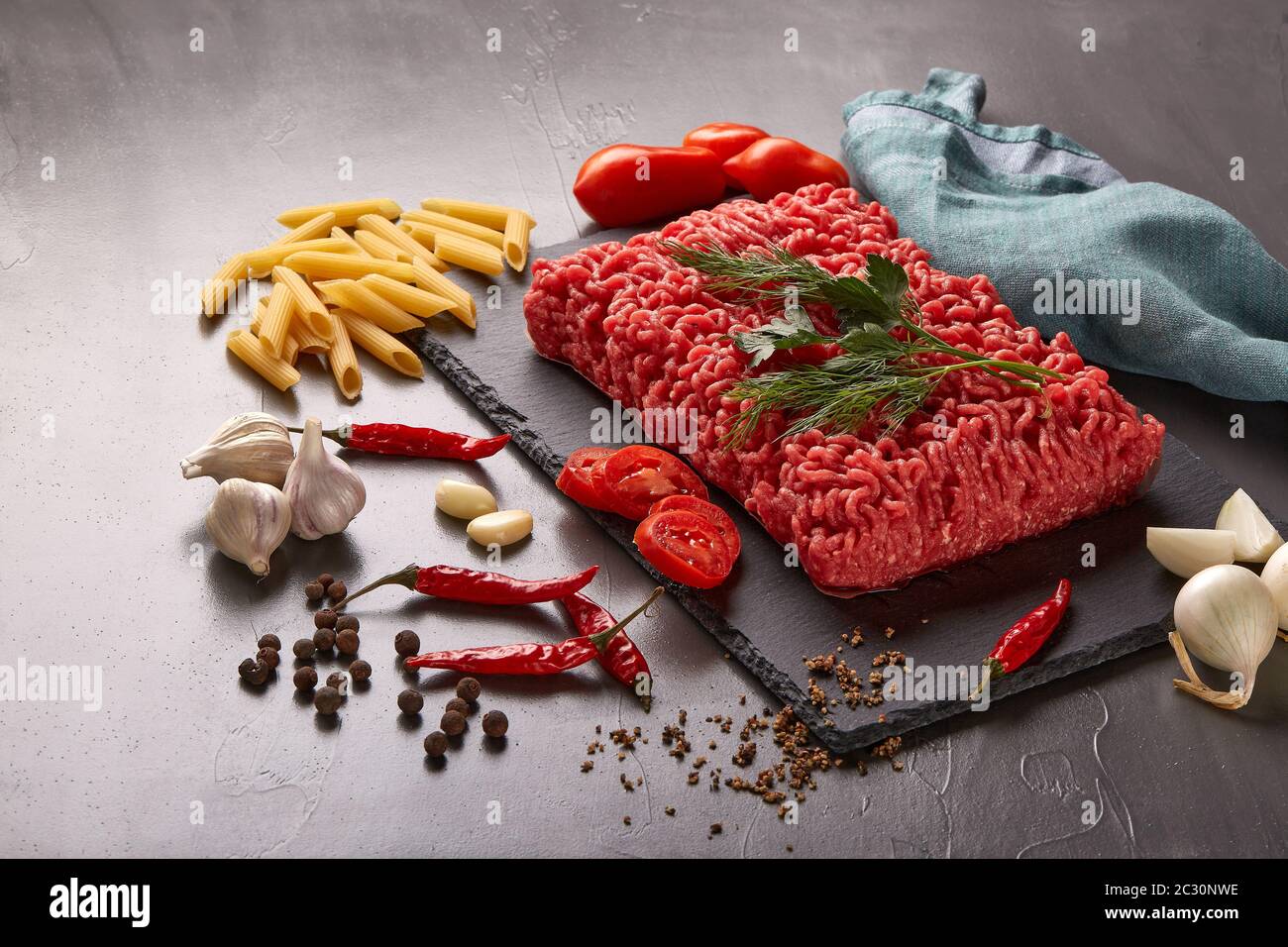 Still life with fresh forcemeat from beef, vegetables, pasta and spices ...
