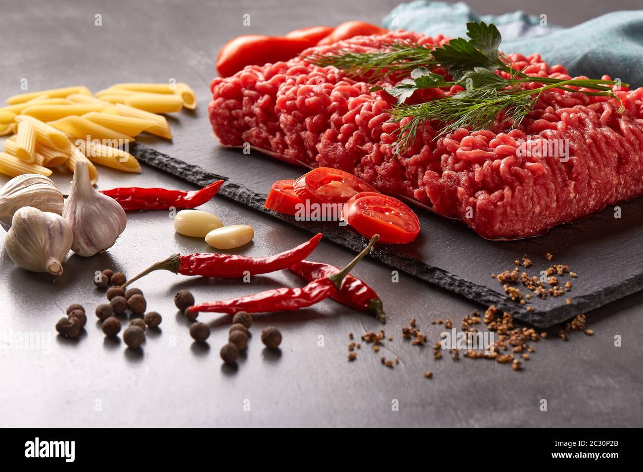 Still life with fresh forcemeat from beef, vegetables, pasta and spices ...