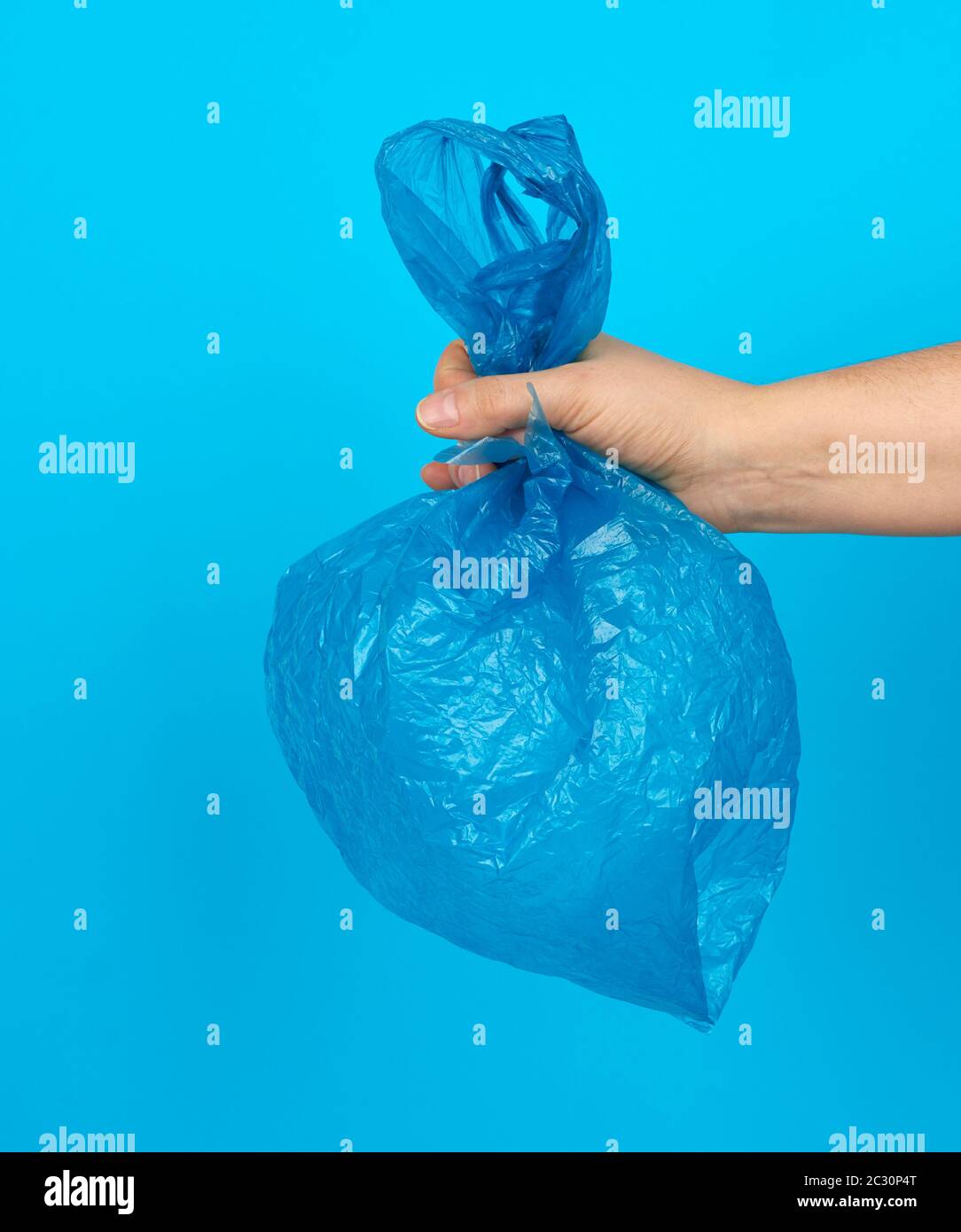 hand holds an empty blue plastic bag on a blue background, concept of ...
