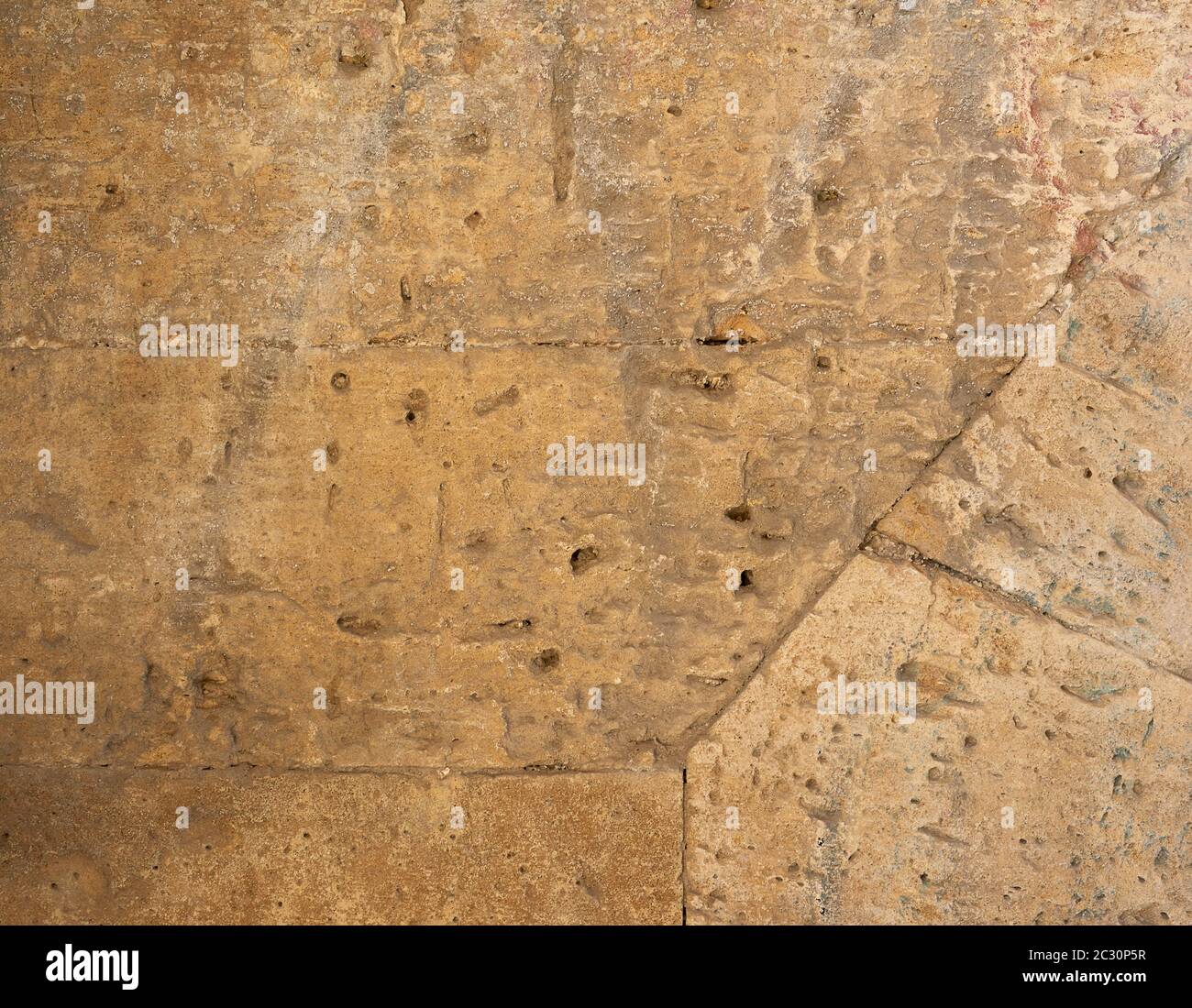 wall of yellow rectangular stones with cement, fragment of ancient ...