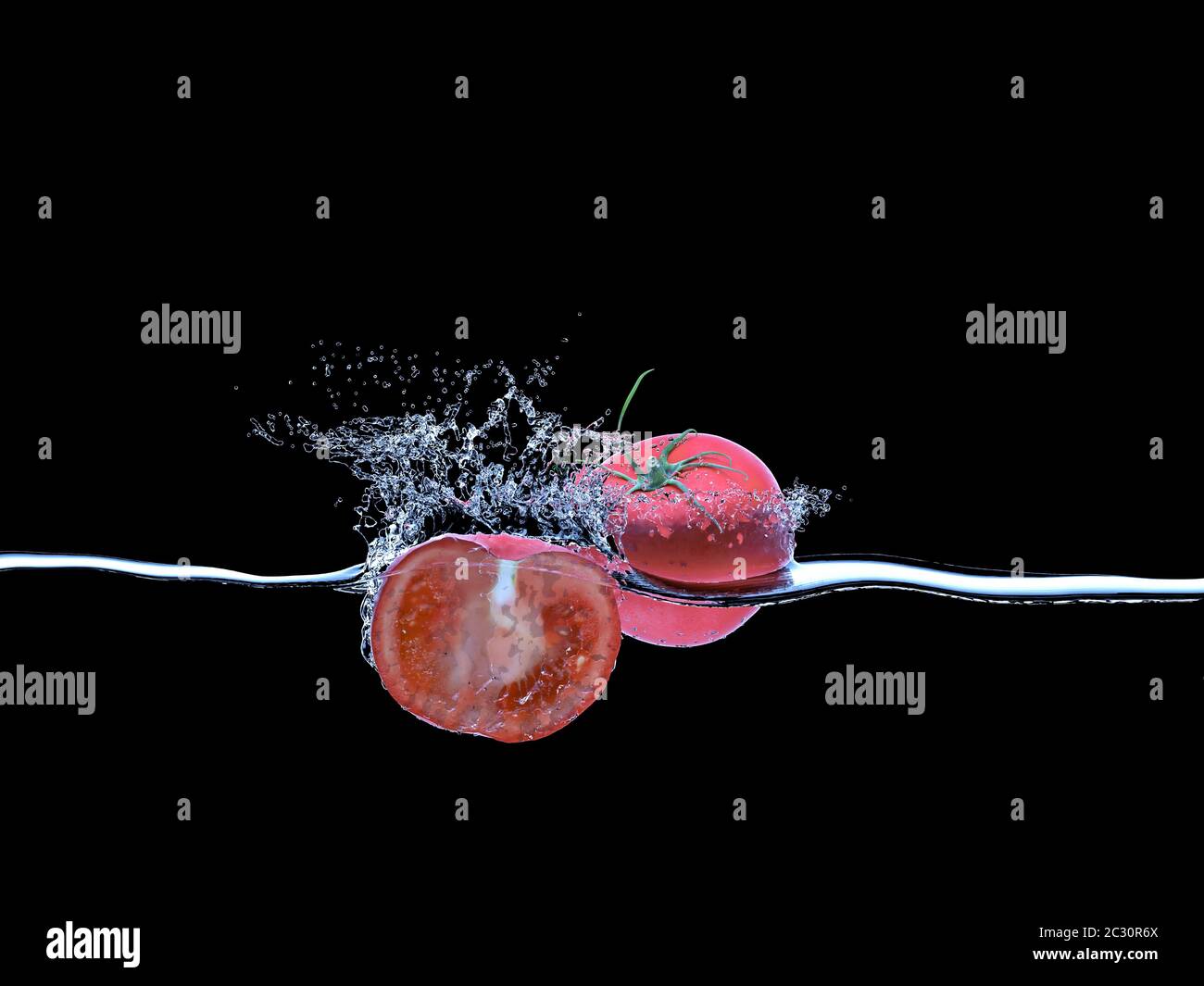 tomatoes falling into water and splashing on black. concept of fresh ...