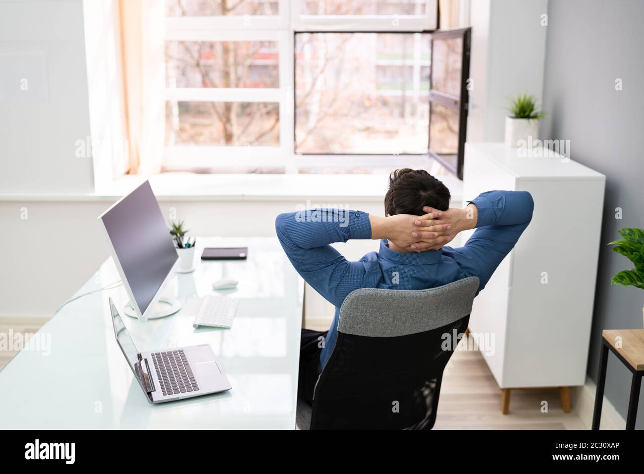 Relaxed Young Businessman Relaxing On Chair Behind Desk At Office Stock ...