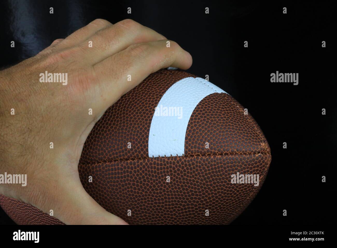 Hand gripping a football Stock Photo - Alamy