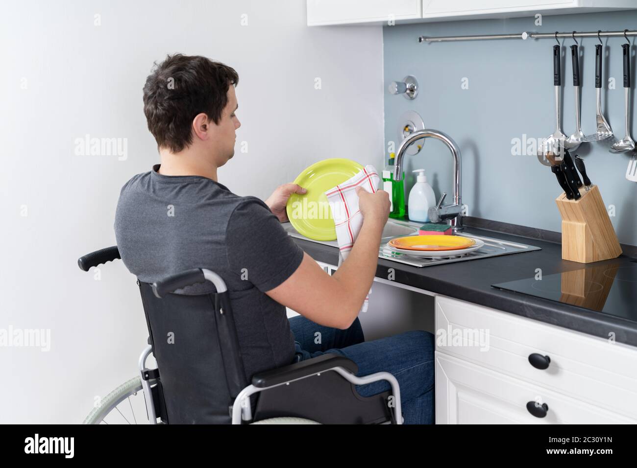 Handicapped Man Sitting On Wheelchair Washing And Cleaning Dishes In ...