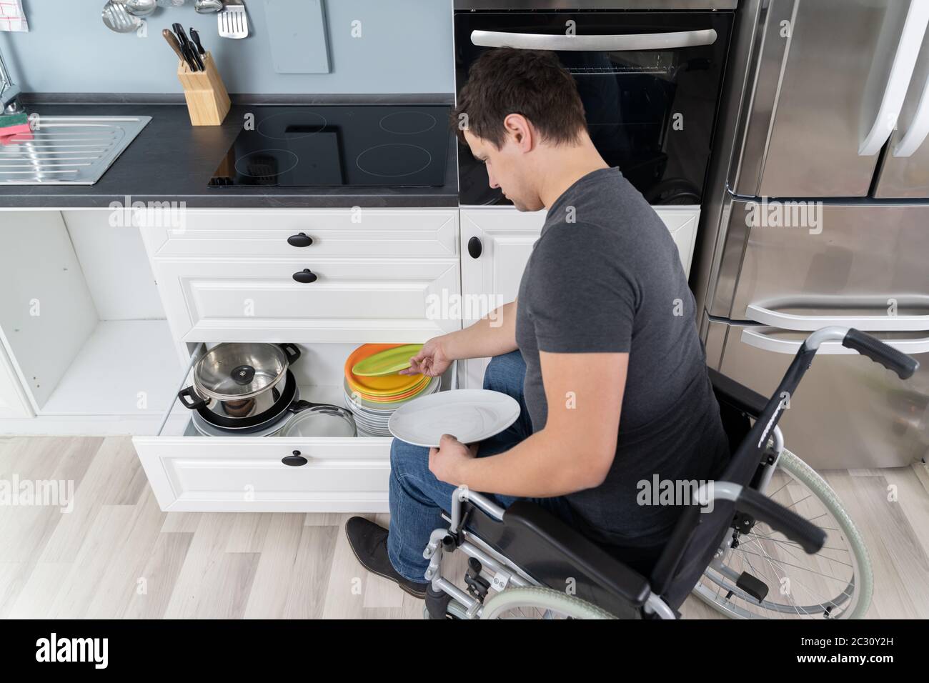Young Happy Disabled Man Sitting On Wheelchair Arranging Plates In ...